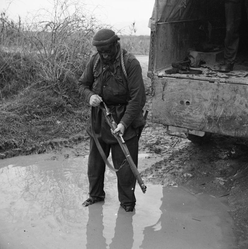 A member of No 9 Commando checks his rifle after a raid on enemy ...