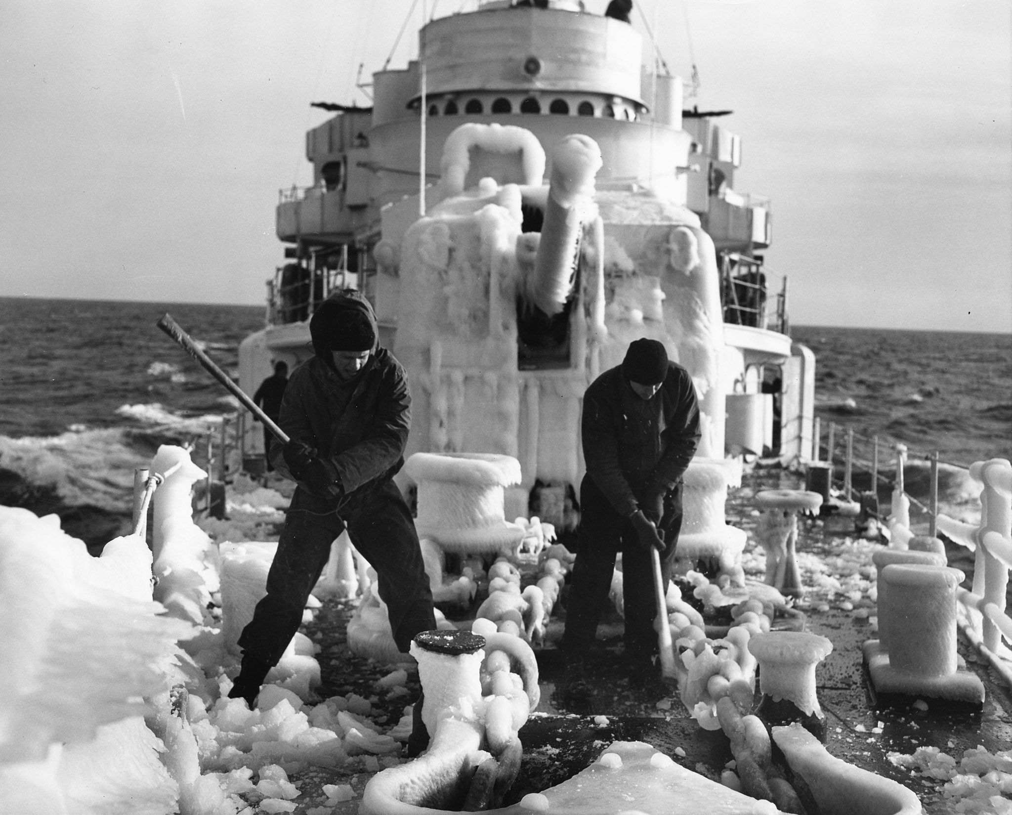 Coast Guardsmen work on breaking the ice that coats the deck of USCG ...